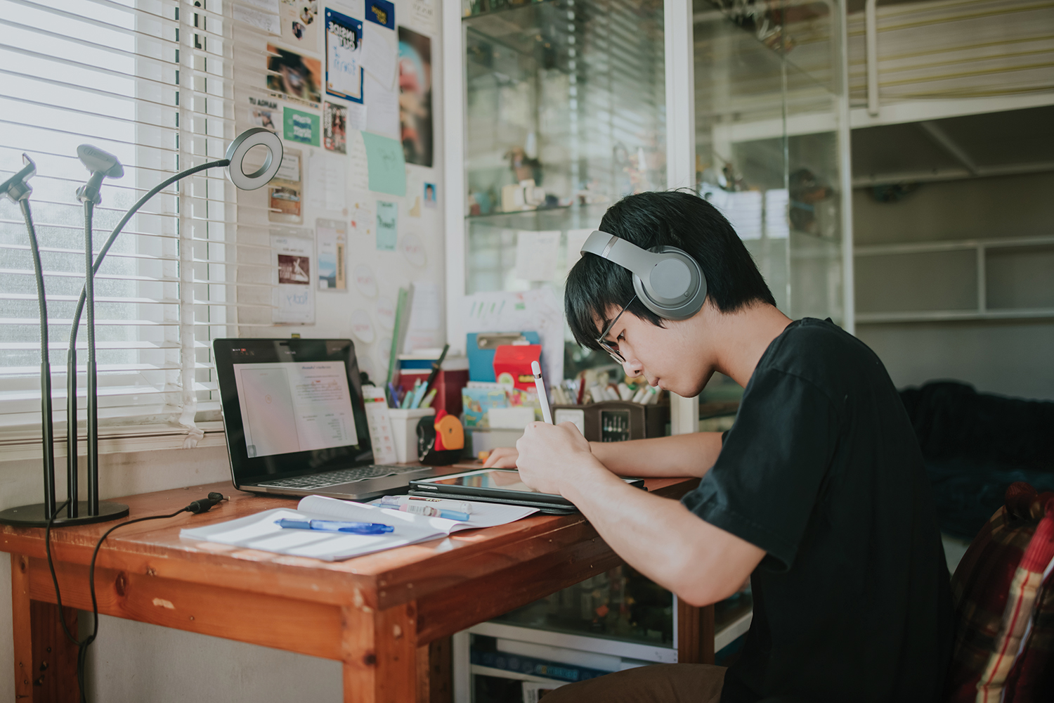 Thai nerd male teenager studying and doing school homework with tablet ...